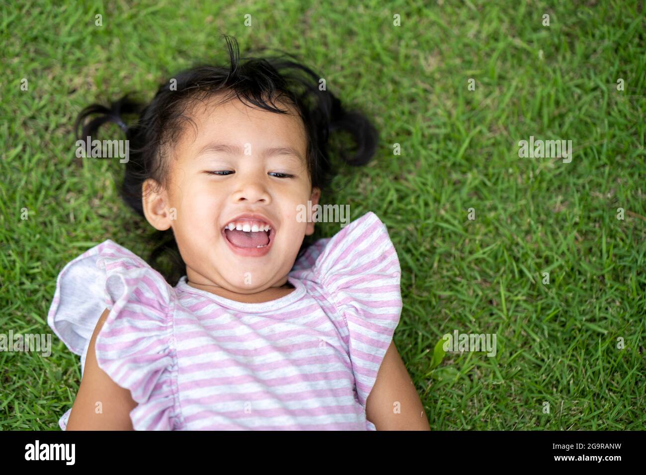 Closeup shot of a Southeast Asian happy girl lying on the grass Stock ...