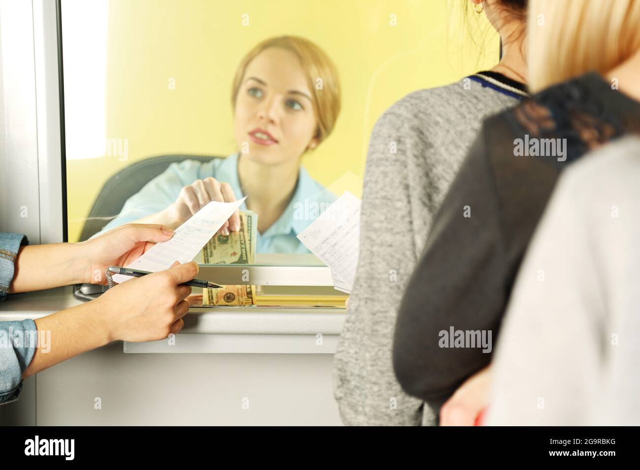 Teller window with working cashier Stock Photo - Alamy