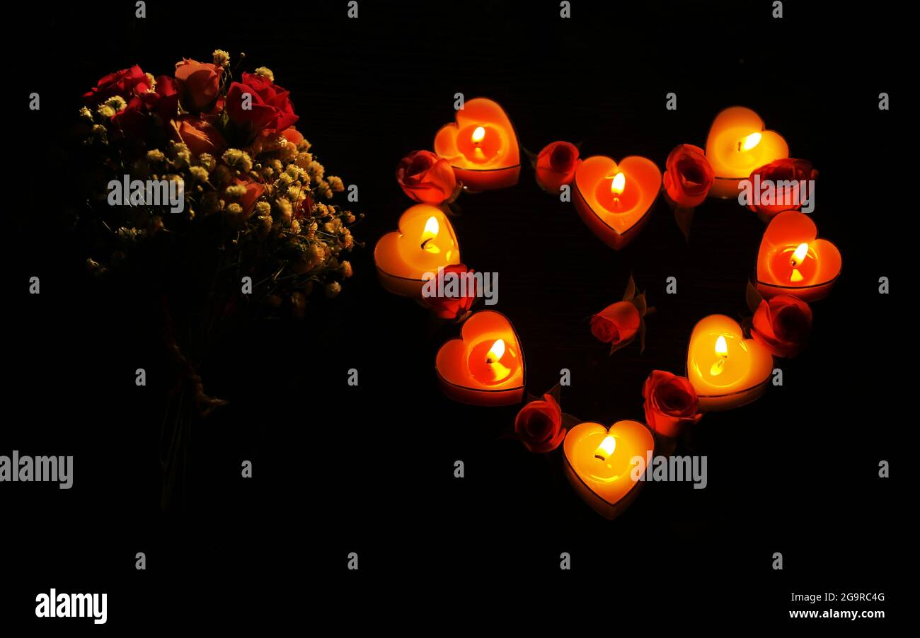 Romantic atmosphere with candle lights and flowers on dark background ...