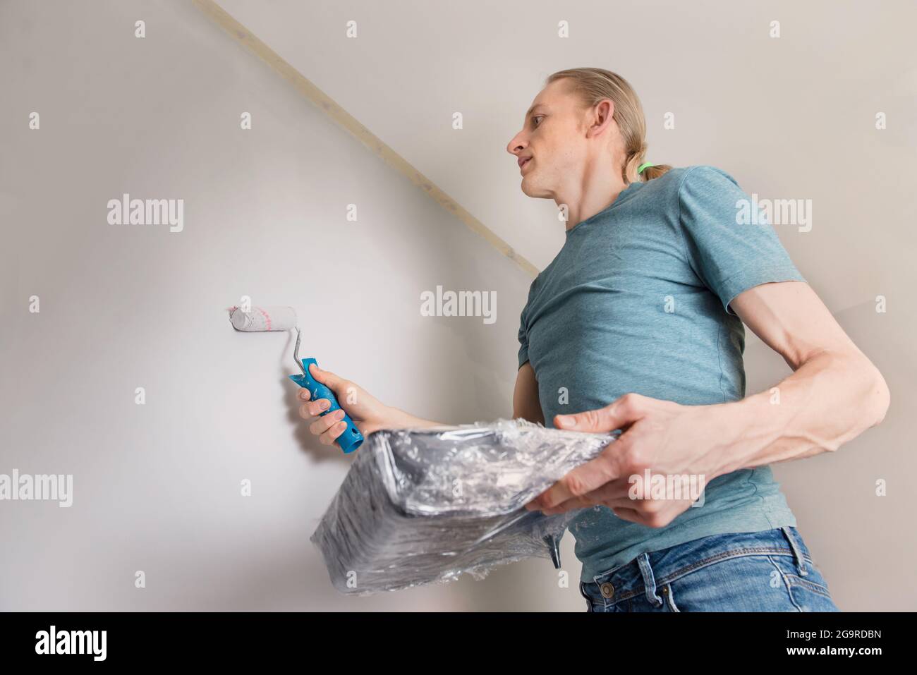 Person holding paint roller over gray wall. Man doing decoration and re ...