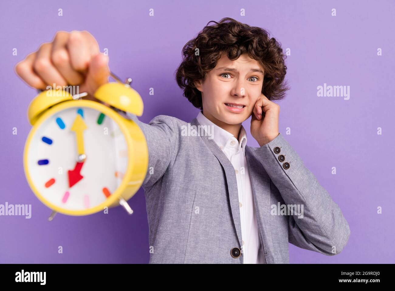 Photo of scared crazy schoolkid hold alarm clock grimace wear grey suit ...