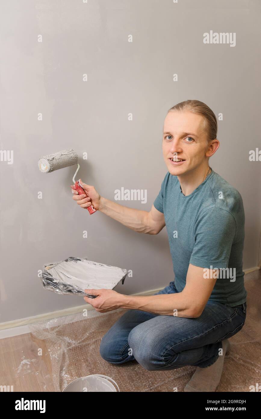 Person holding paint roller over gray wall. Man doing decoration and re ...