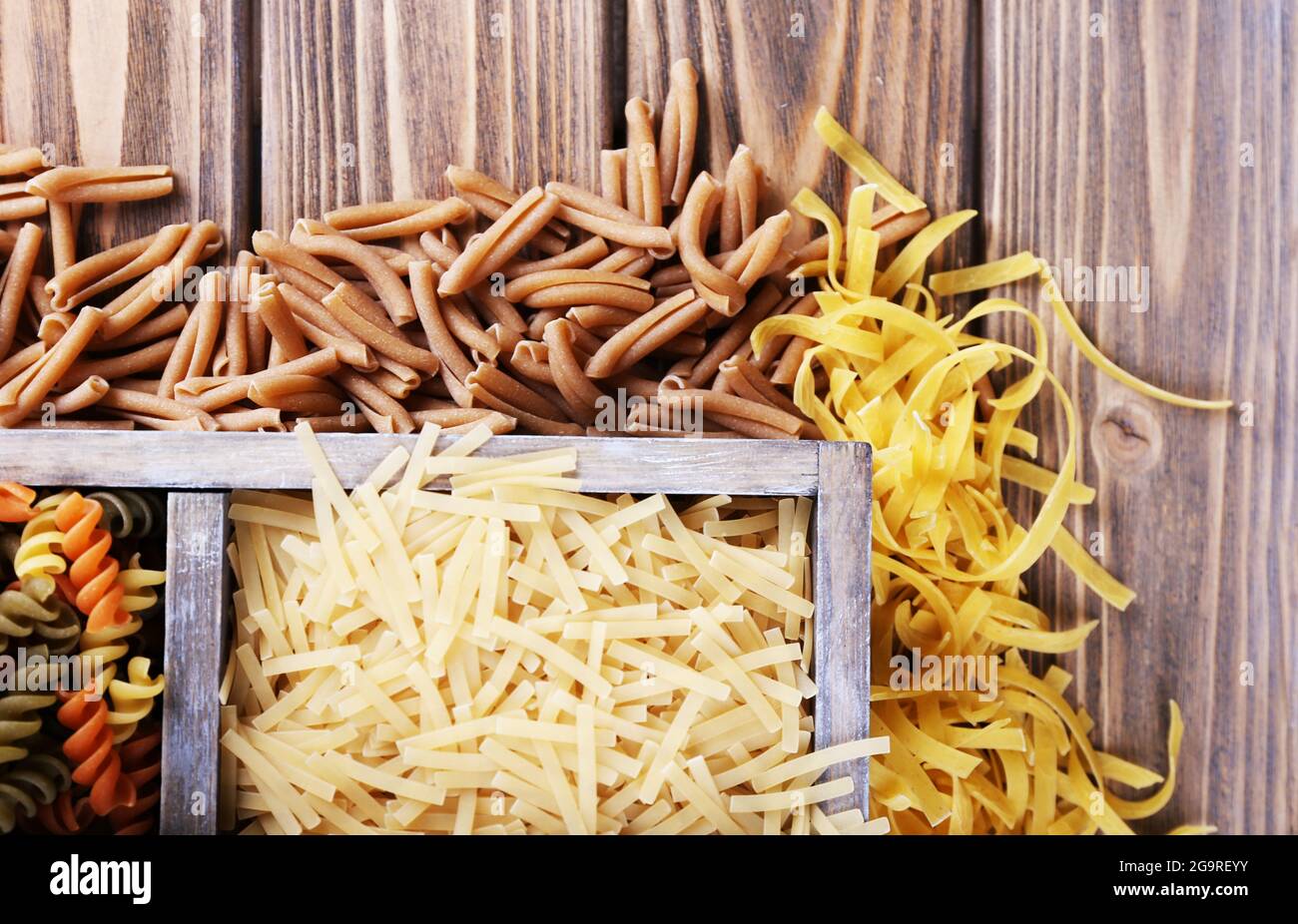 Different types of pasta in box on wooden background Stock Photo - Alamy