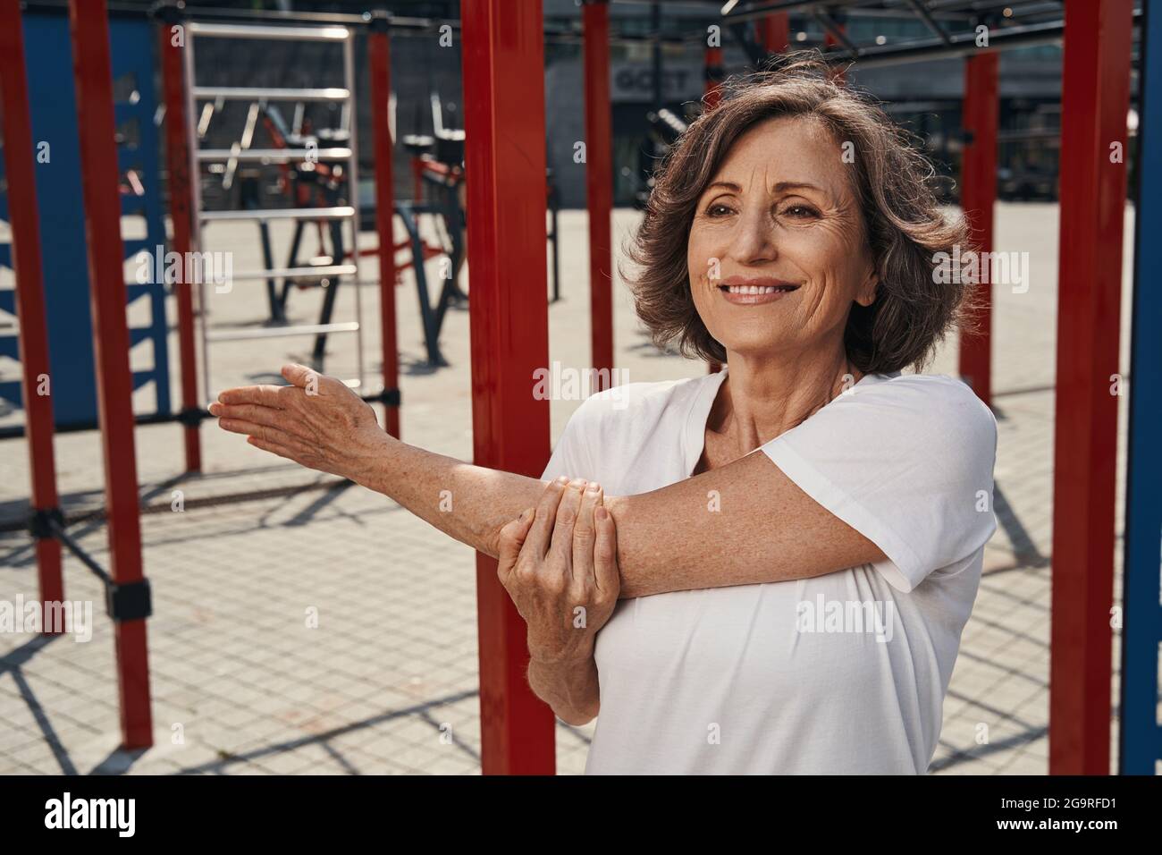 Merry mature woman doing workout on sports ground Stock Photo - Alamy