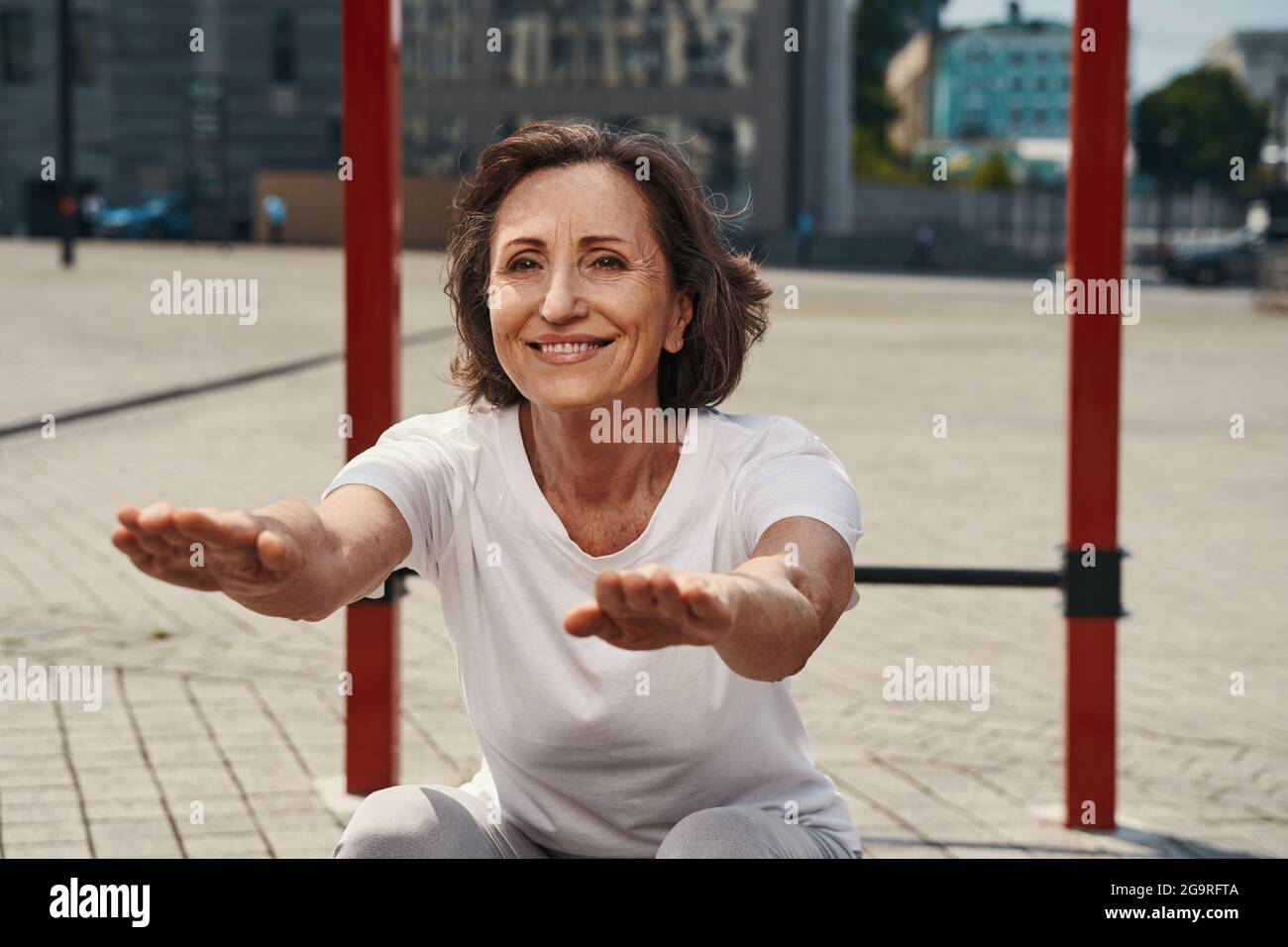 Happy elderly fit woman doing squats outdoors Stock Photo - Alamy