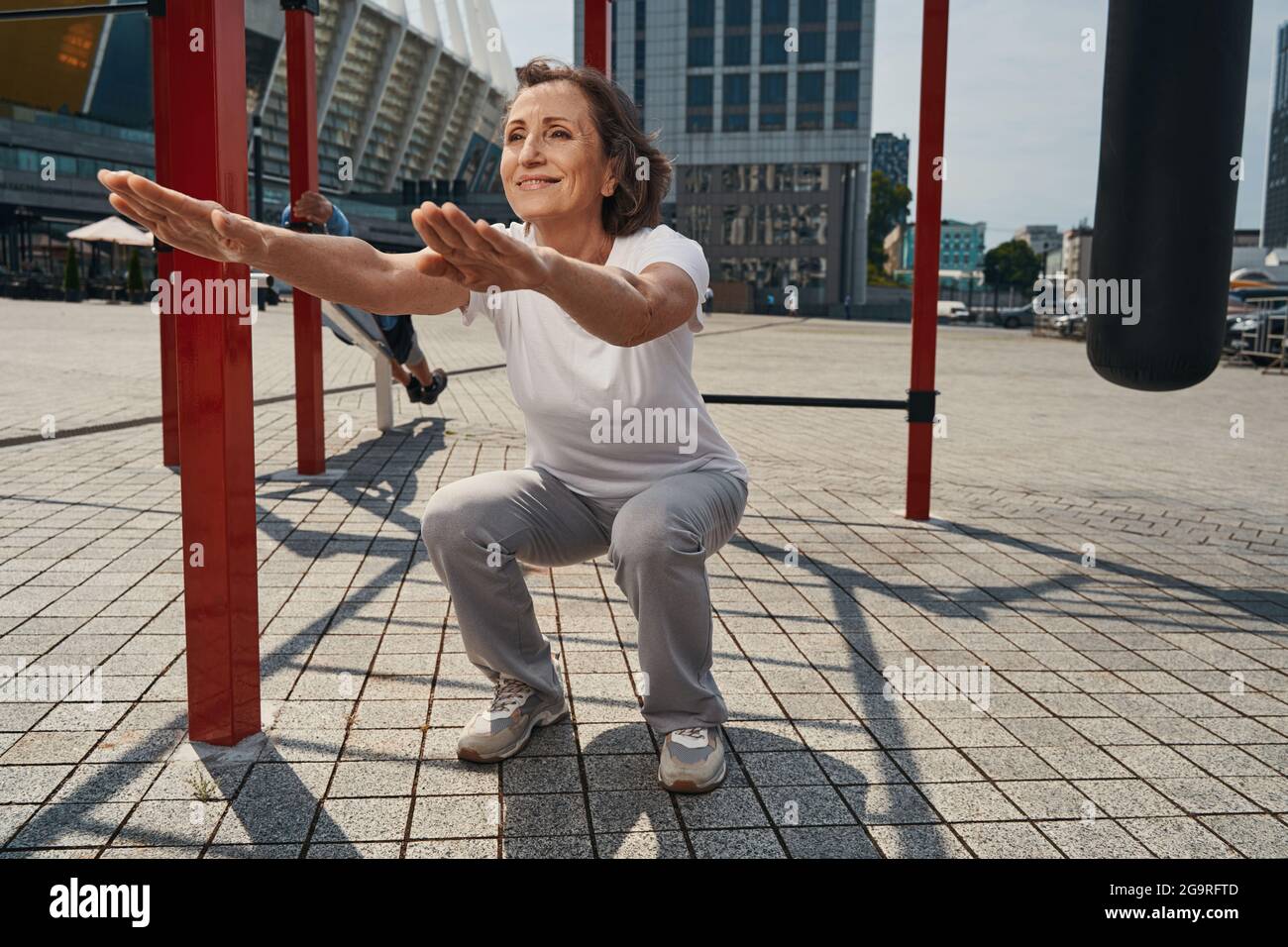 Happy adult fit lady doing squats outdoors Stock Photo - Alamy