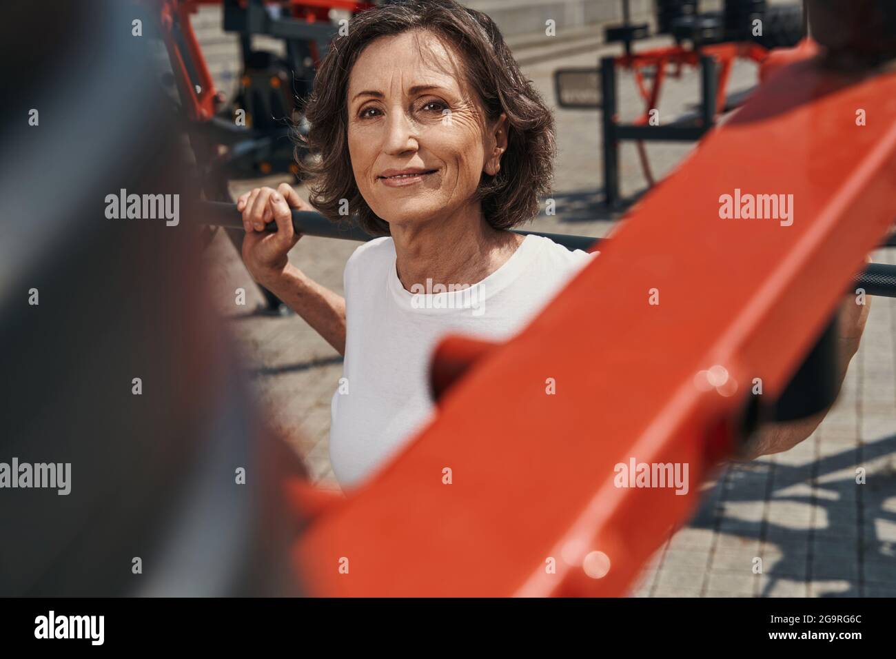 Smiling mature woman working out on sports ground Stock Photo - Alamy