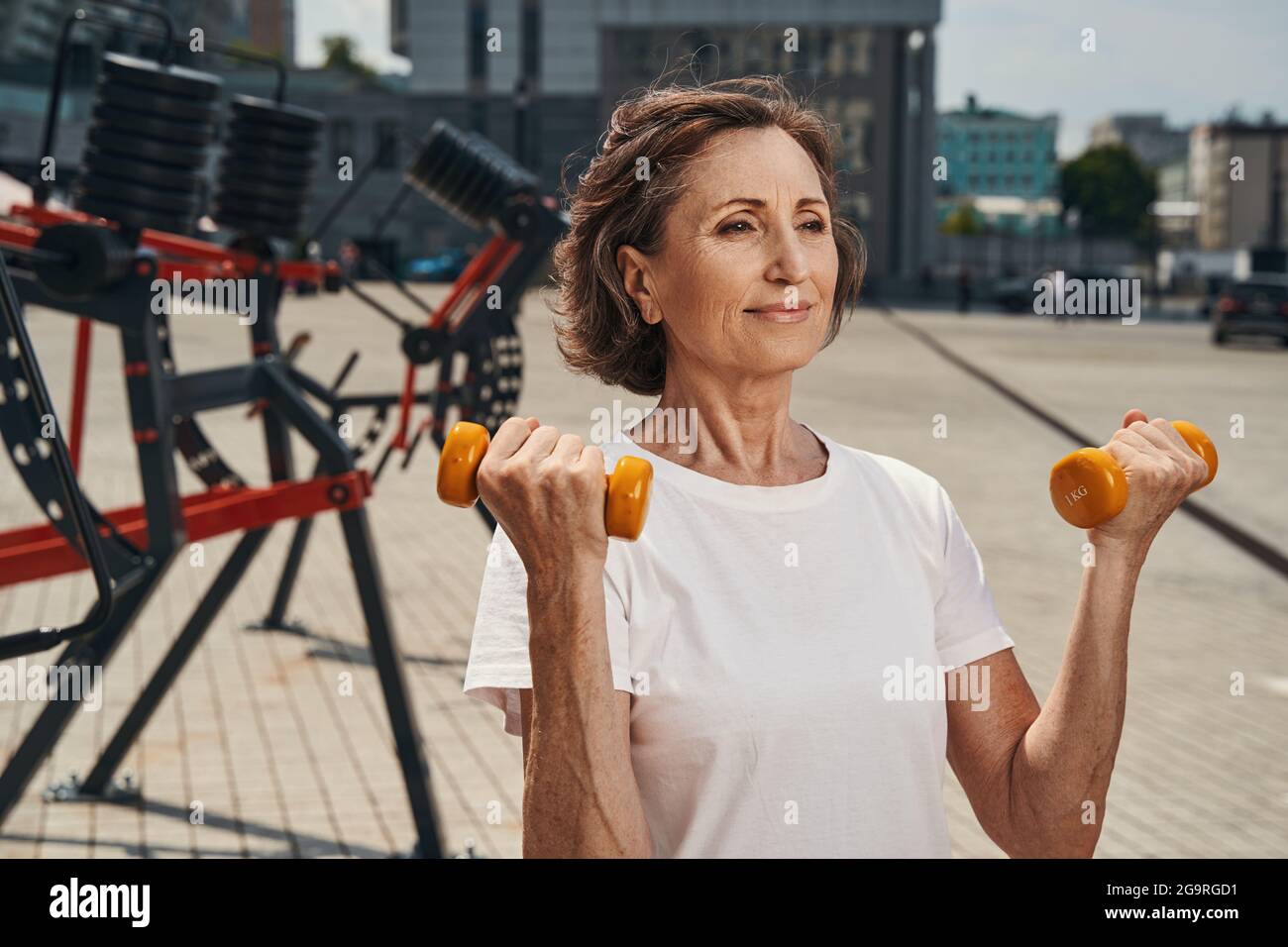 Happy senior female exercising with dumbbells outdoors Stock Photo - Alamy