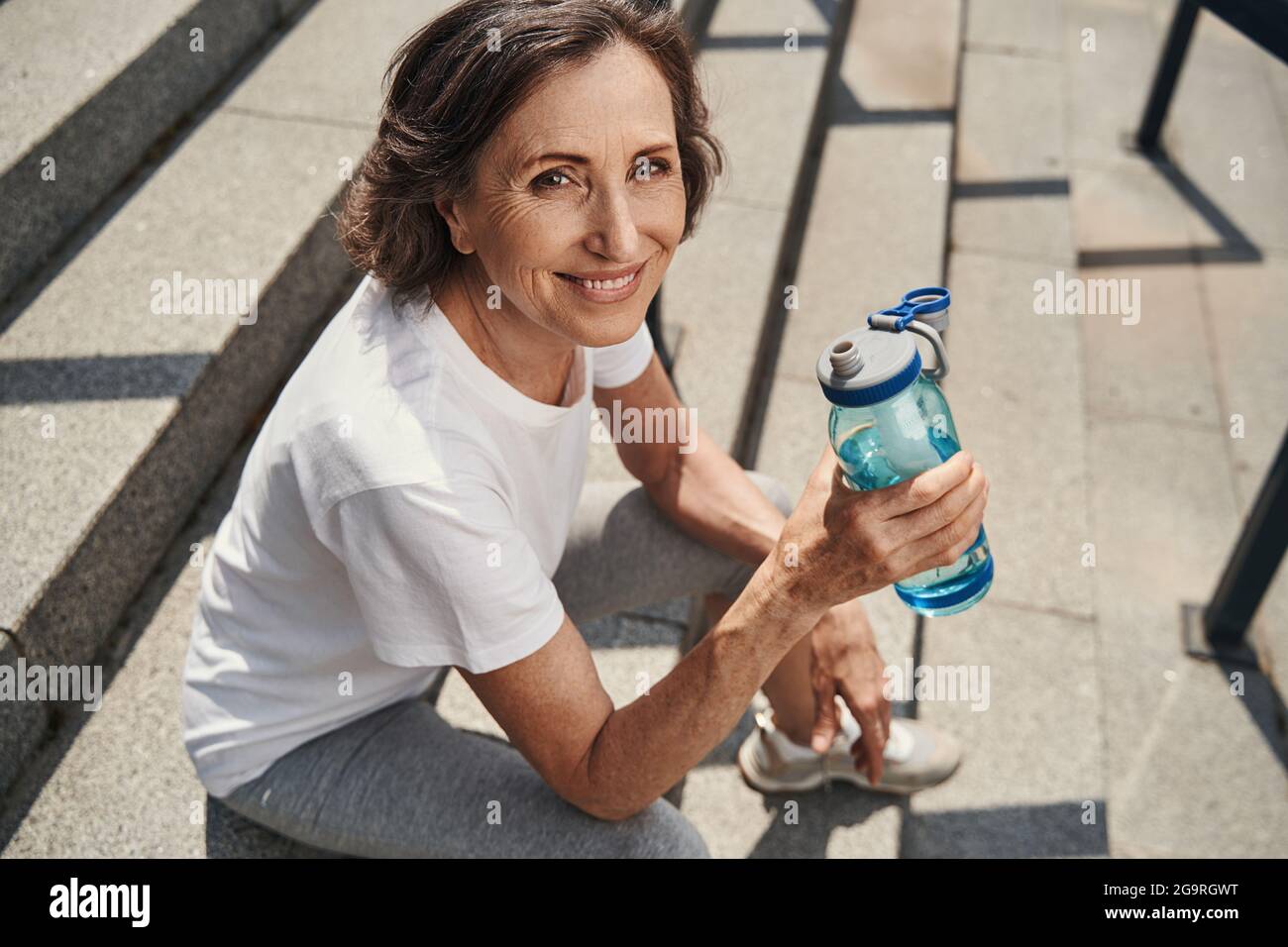Happy aged pretty female drinking water outdoors Stock Photo - Alamy