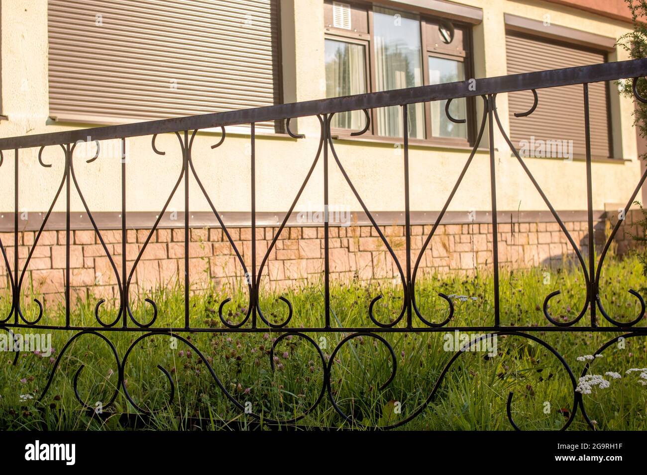 Forged fence on background of lawn and windows of building Stock Photo ...