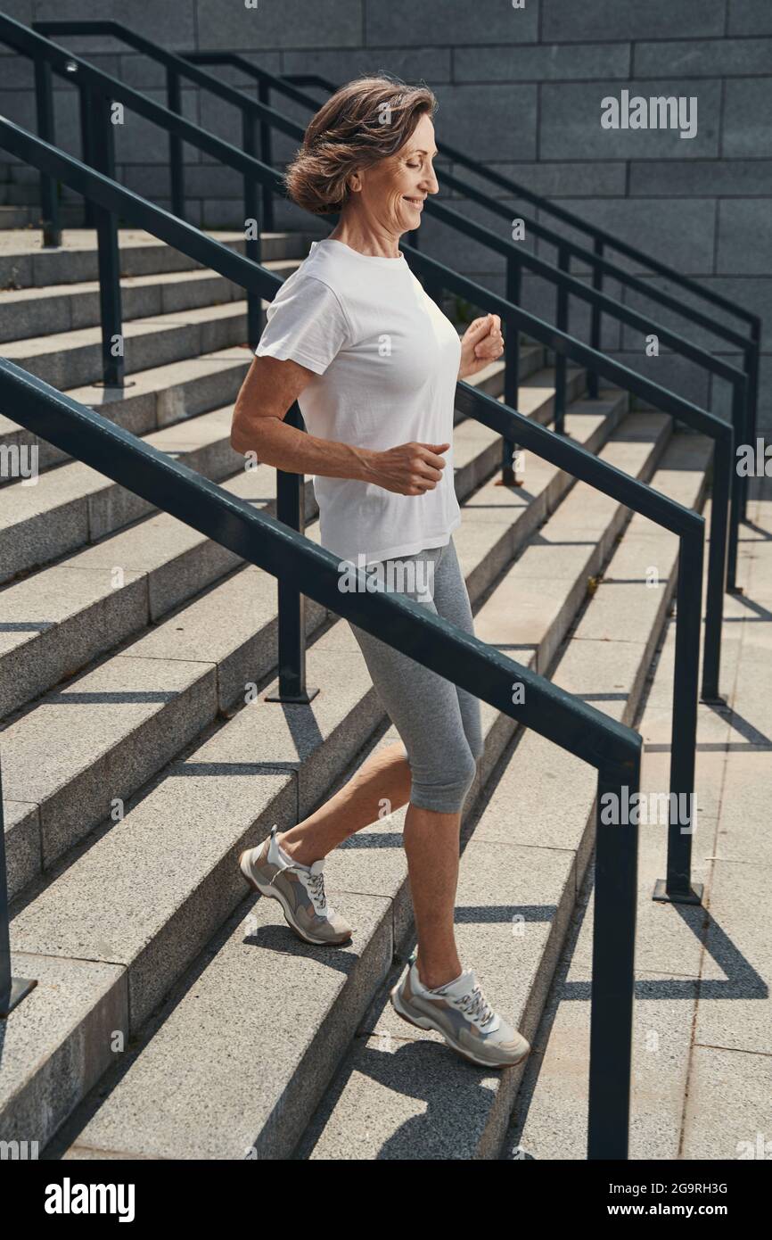 Happy aged woman doing cardio training outdoors Stock Photo - Alamy