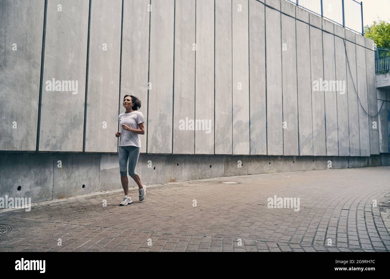 Slim mature woman running among urban scape Stock Photo - Alamy