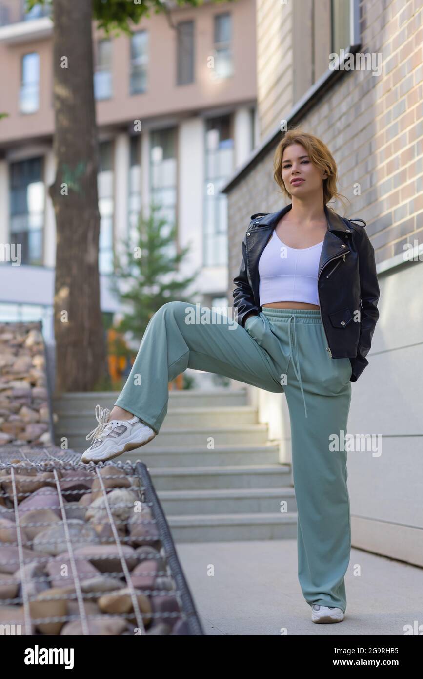 Portrait of a young pretty woman in blue shorts sitting on a bench in ...