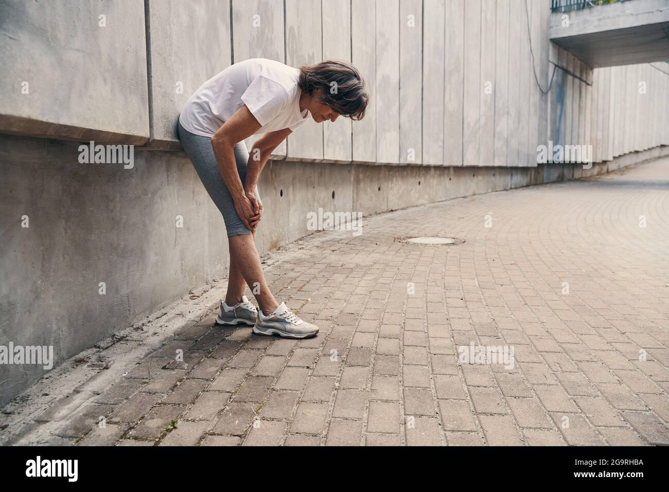 Elderly fit woman having leg hurt during workout Stock Photo - Alamy