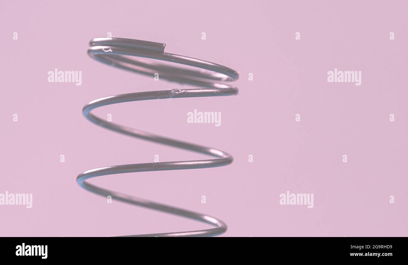 Details of a metal spring on pink cloth Stock Photo - Alamy