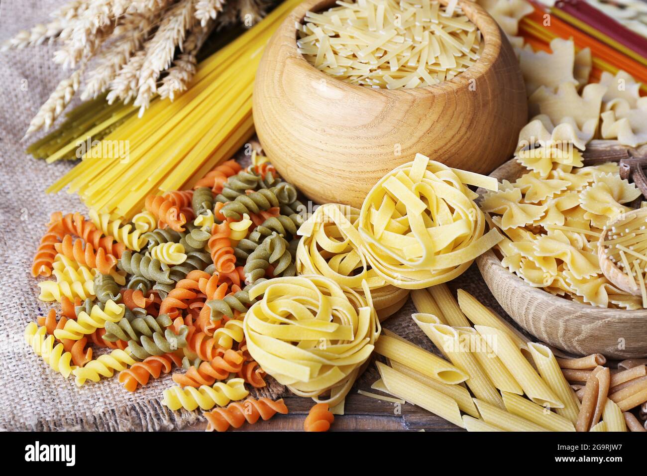Different types of pasta with wheat on wooden table background Stock ...