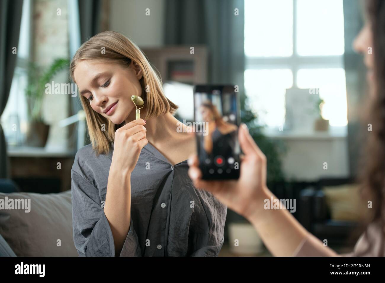 Hand of young woman with smartphone shooting her friend using massage ...