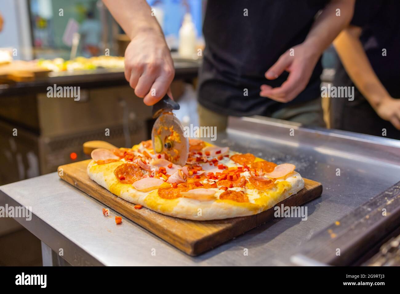 slicing the finished pizza with male hands with a knife Stock Photo - Alamy