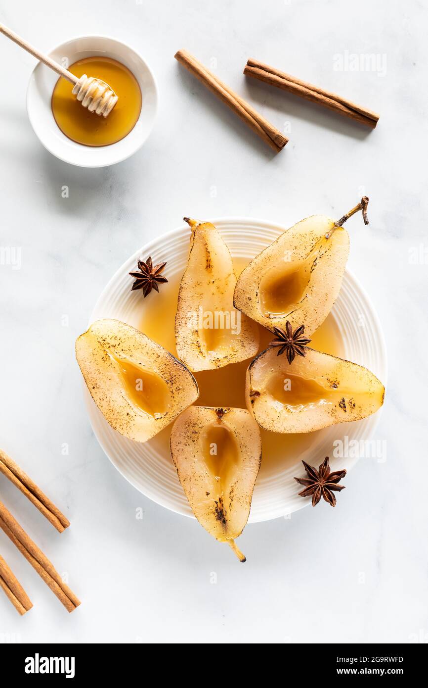 Top down view of poached pears served with honey, cinnamon sticks and ...