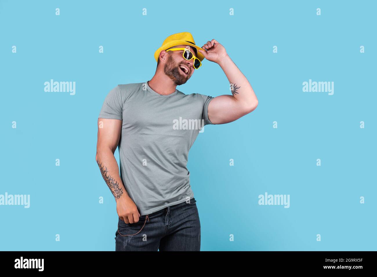 Fashionable muscular bearded emotional man in yellow straw hat posing ...