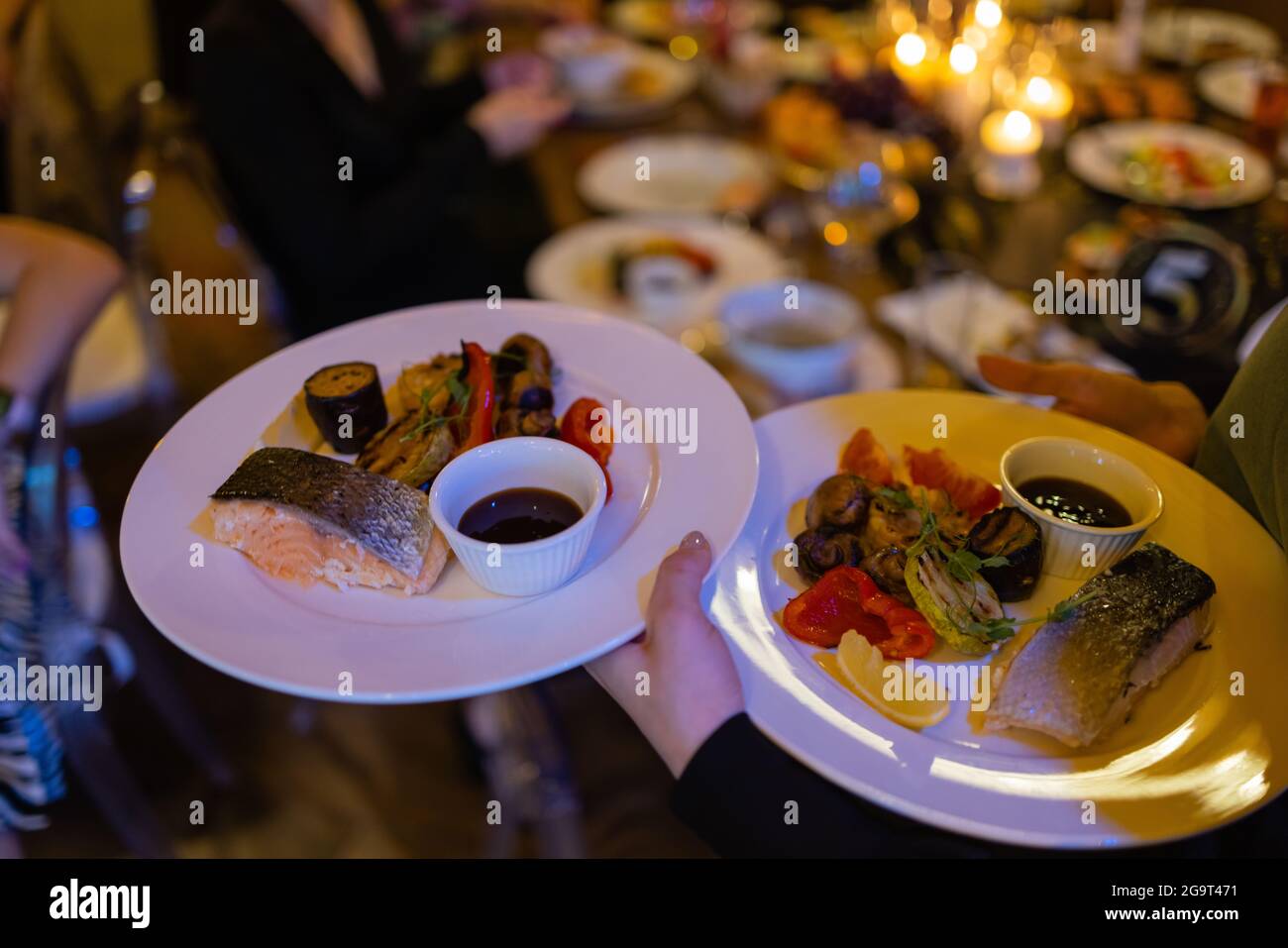 Two meat plate with salad leaves and summer salad in waiter's hand ...