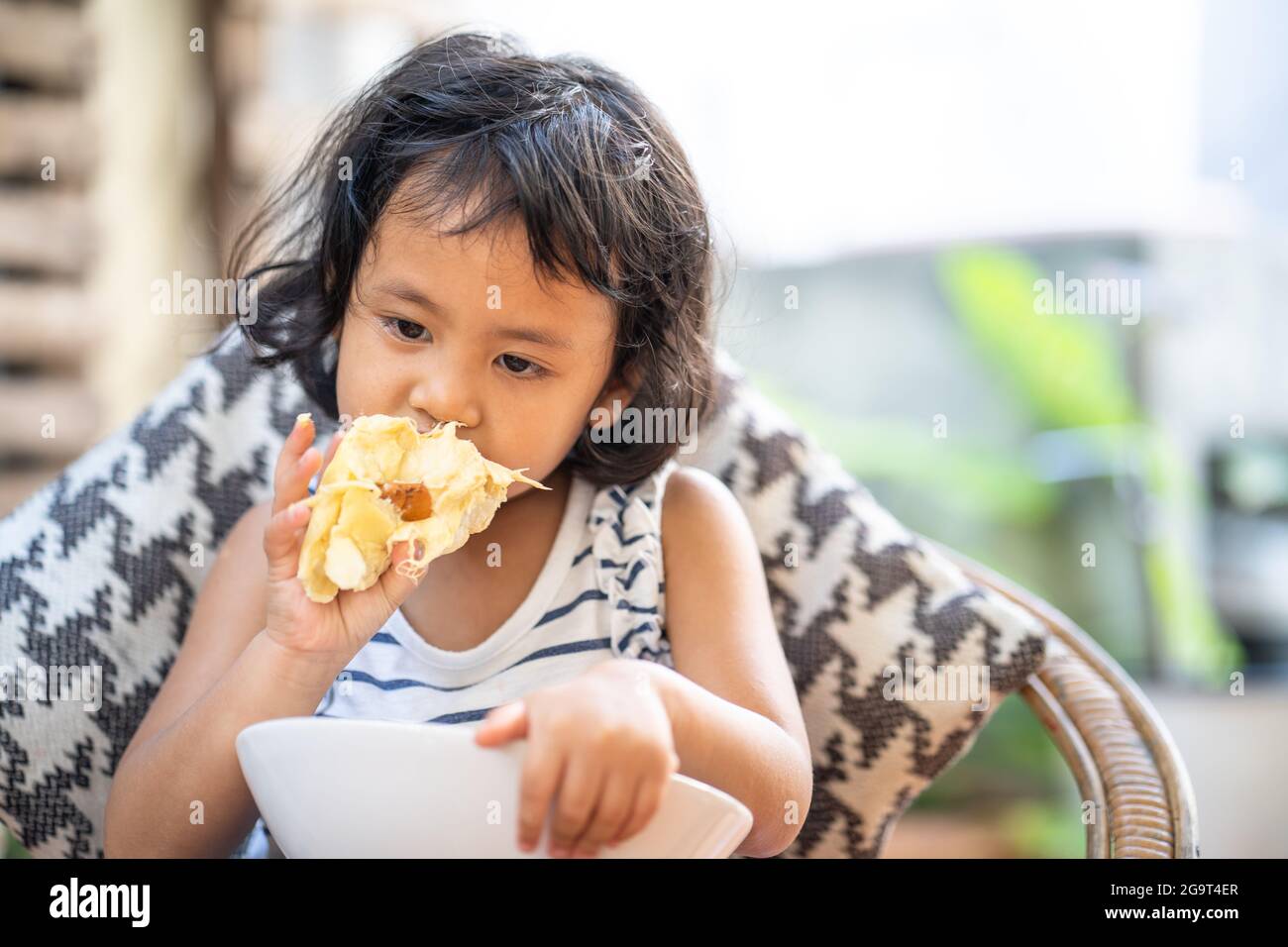 Cute Southeast Asian female child eating a pastry Stock Photo - Alamy