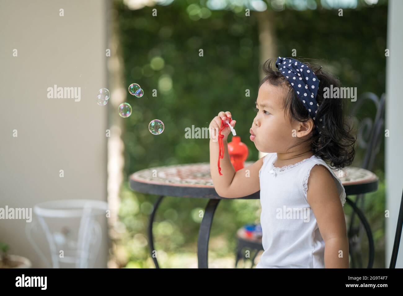 Cute Southeast Asian female child blowing bubbles in a park Stock Photo ...