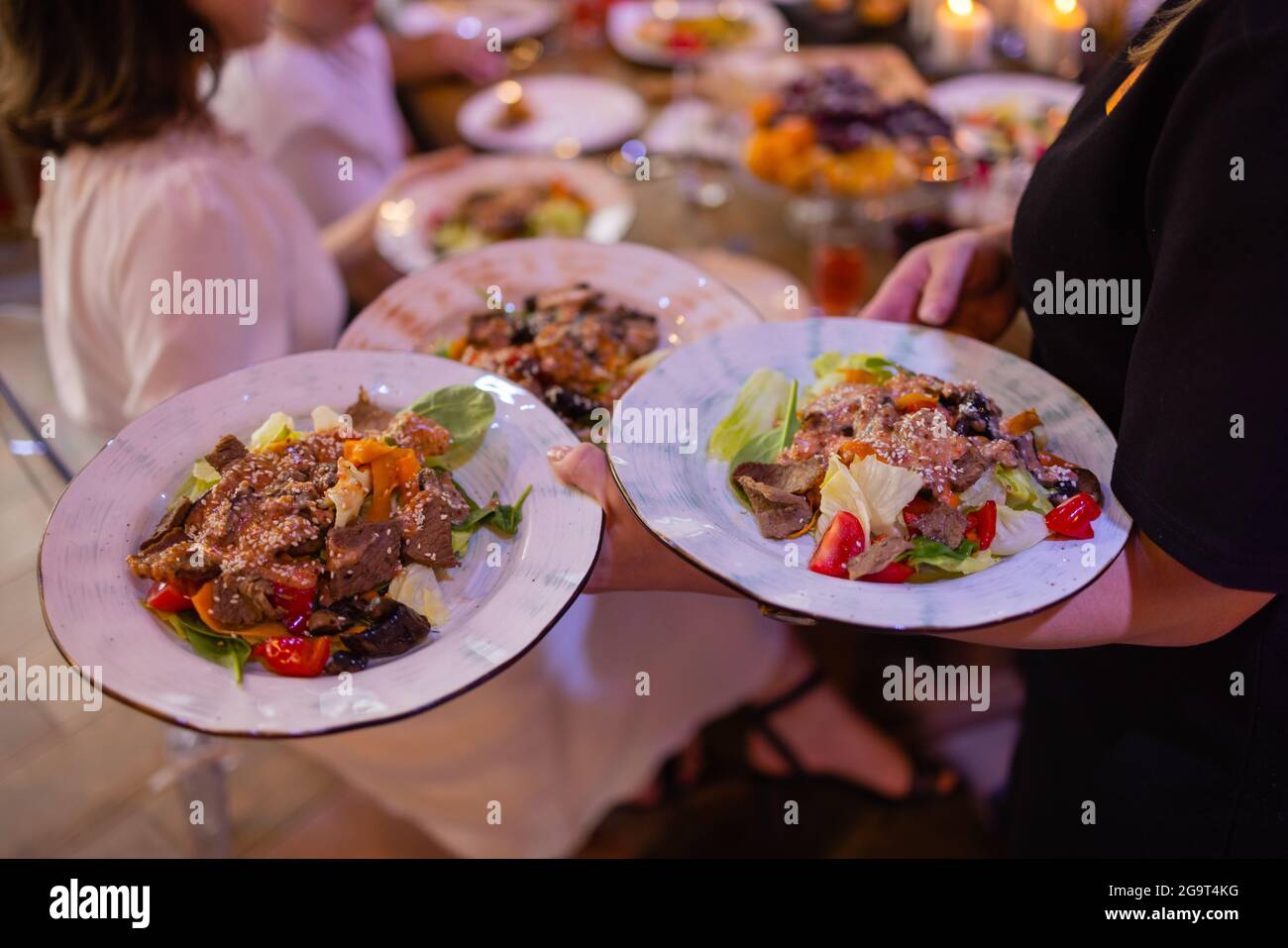 Two meat plate with salad leaves and summer salad in waiter's hand ...