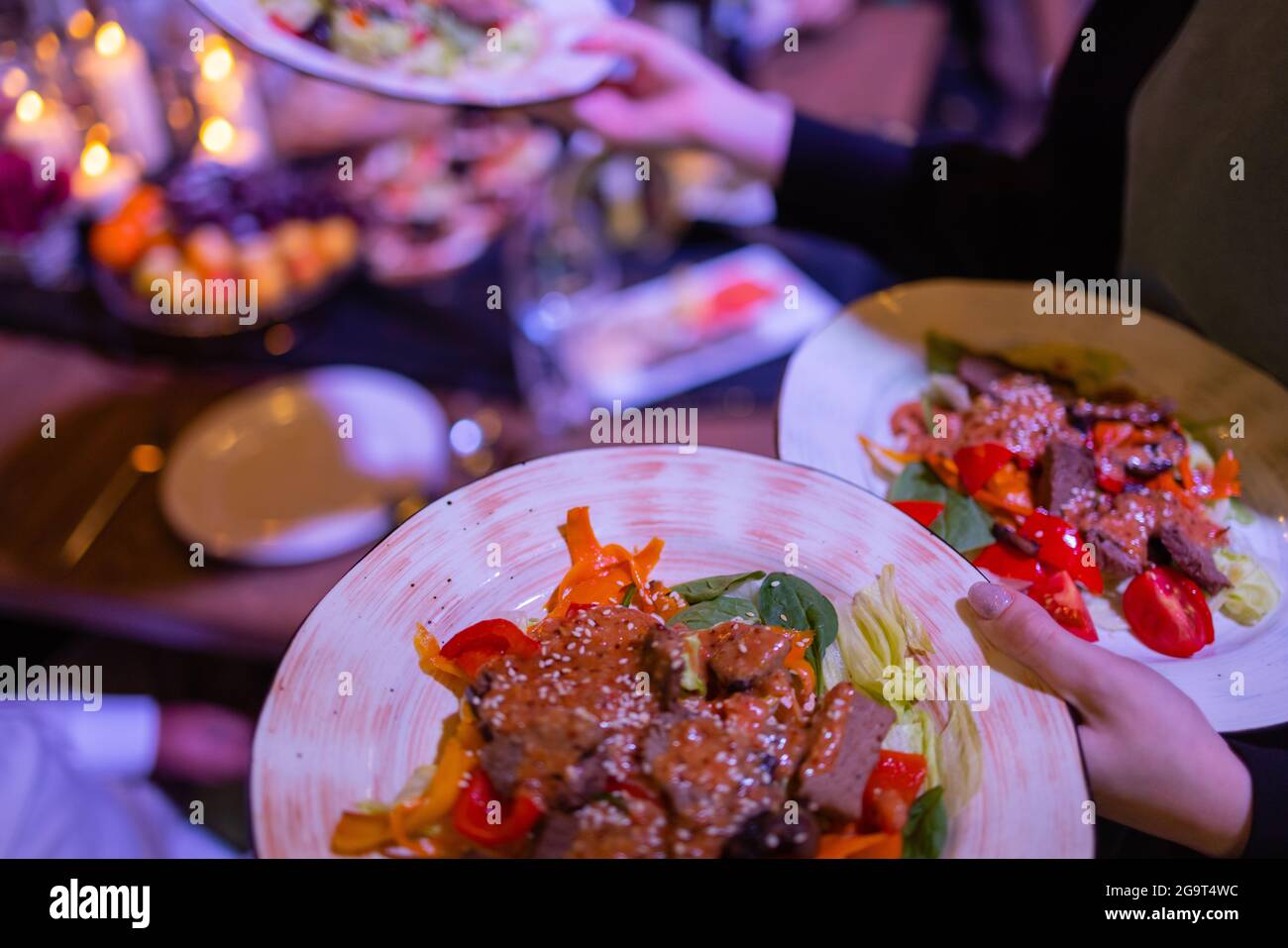 Two meat plate with salad leaves and summer salad in waiter's hand ...