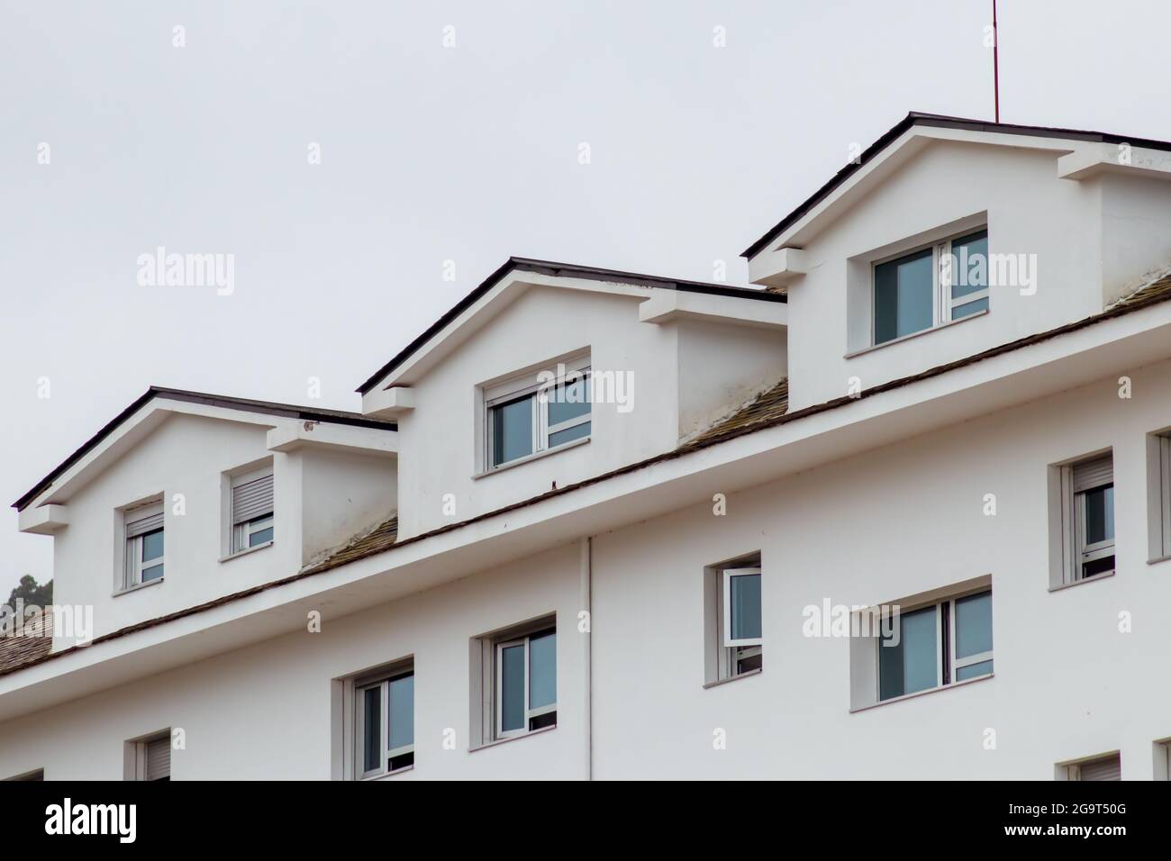 Calm shot of dormers on a white building roof with blue reflective ...