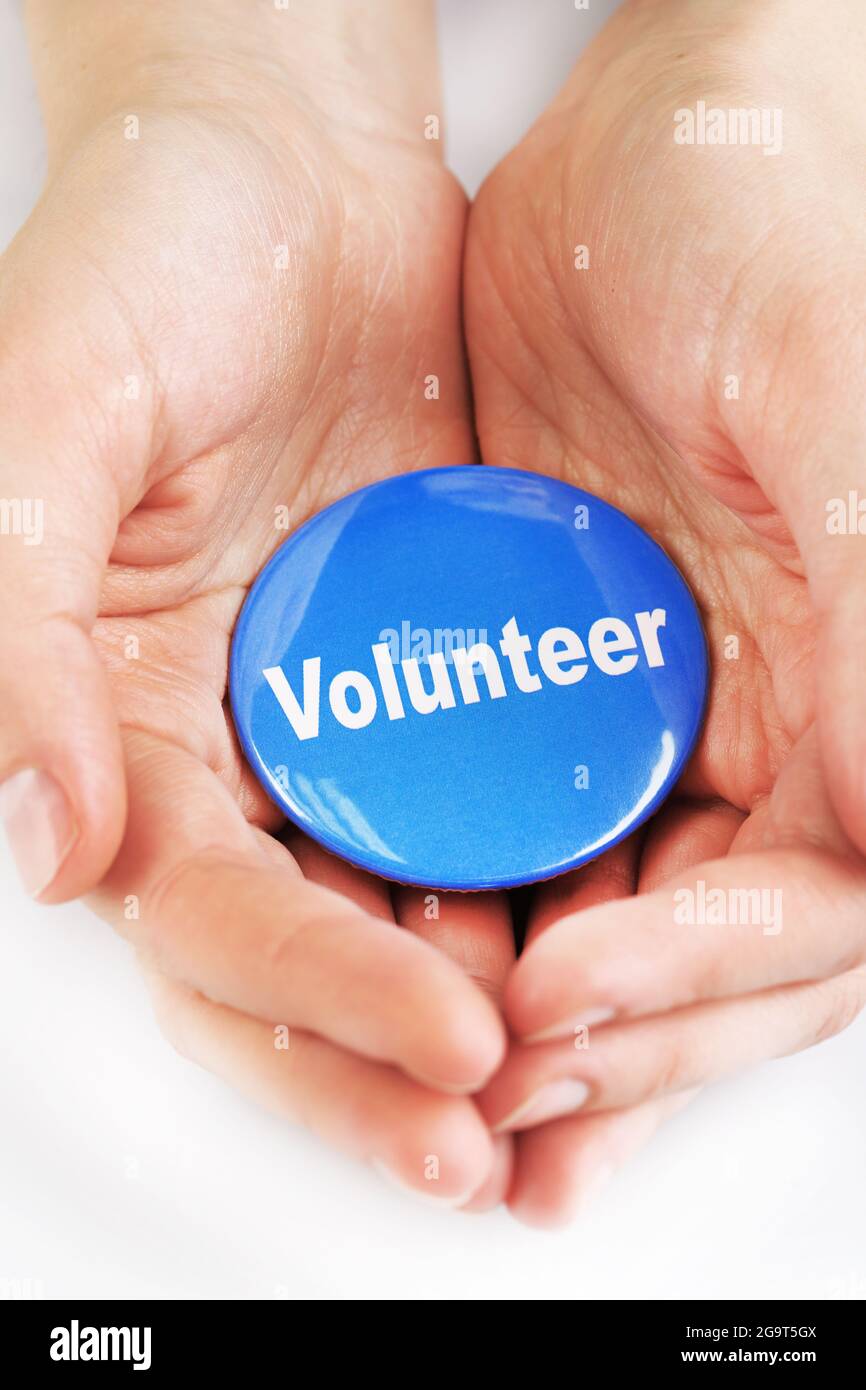 Round volunteer button in hands isolated on white Stock Photo - Alamy