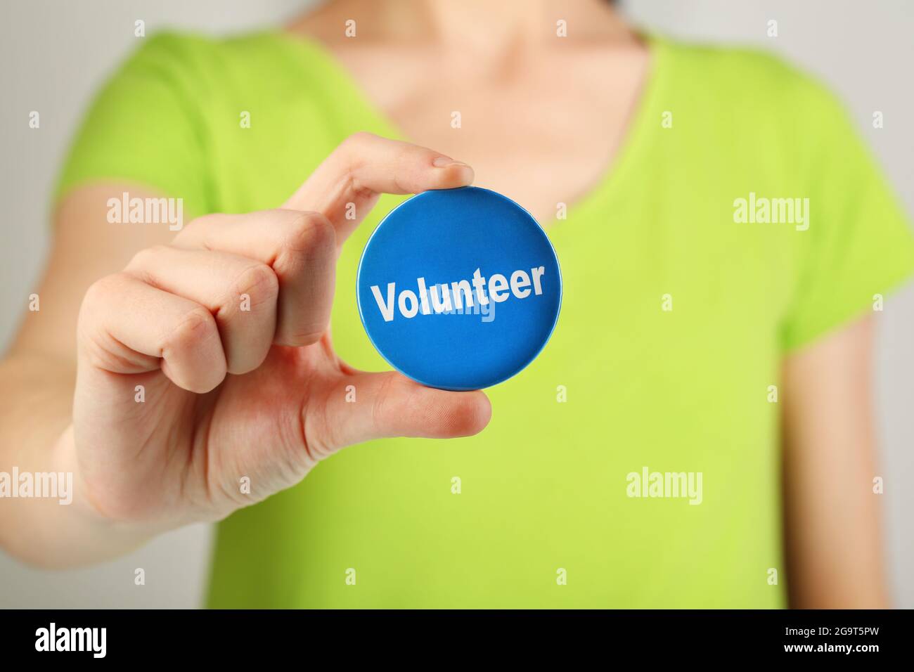 Round volunteer button in hand of girl isolated on white Stock Photo ...