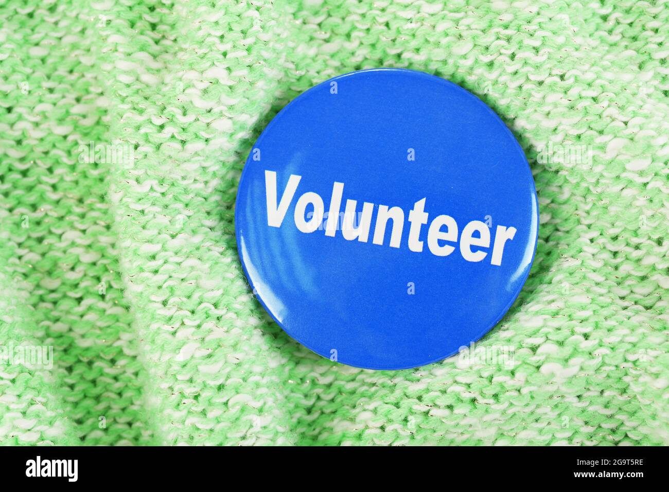 Round volunteer button on cloth background Stock Photo - Alamy