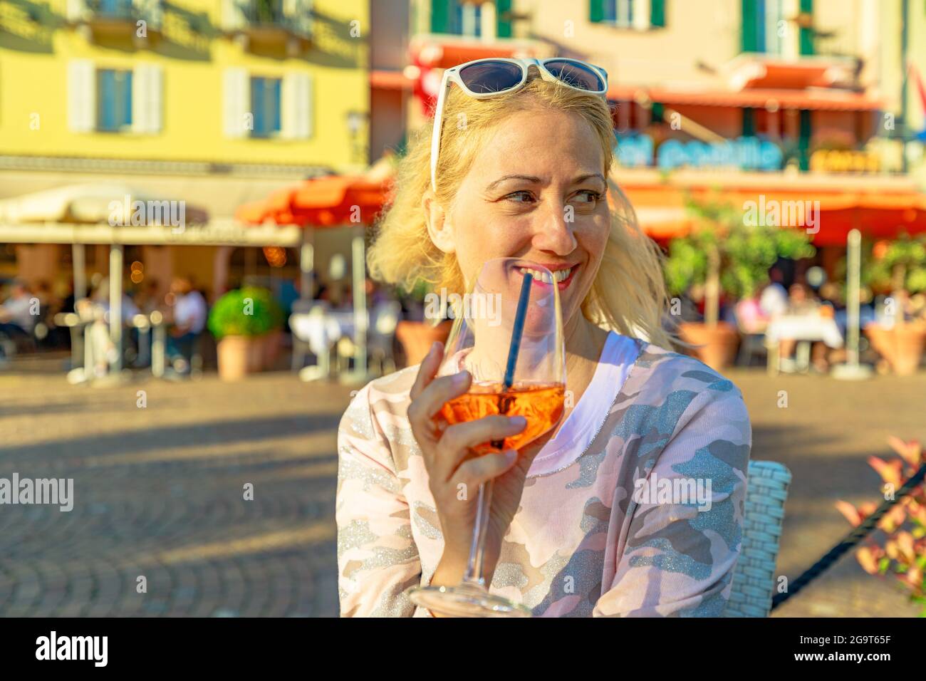 Woman tourist drinking a sunset cocktail by the lakefront in an open ...