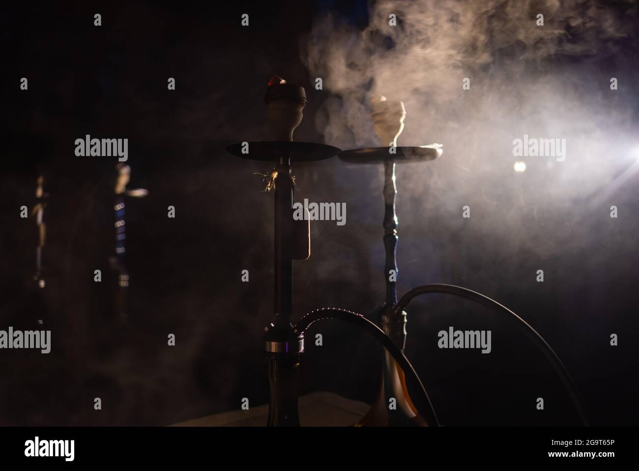 Hookah hot coals on shisha bowl making clouds of steam at dark room ...