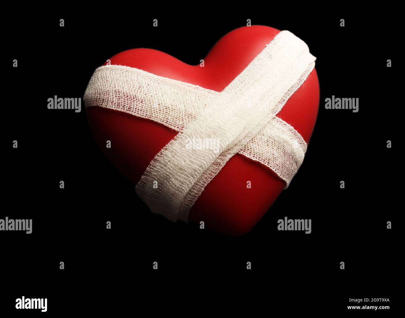 Tied heart with bandage on black background Stock Photo - Alamy