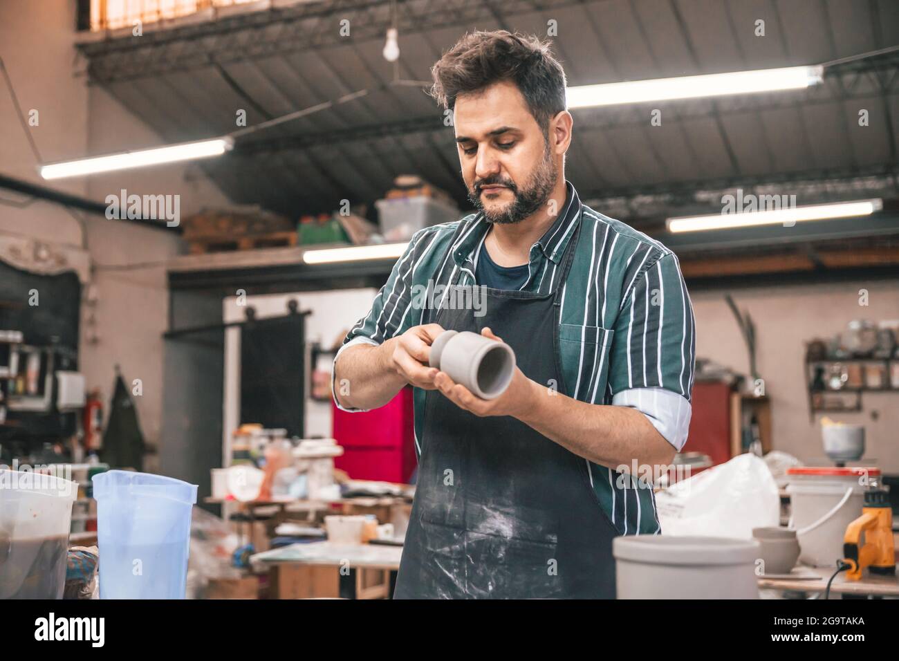 Shallow focus of an adult Hispanic man making a clay pot in a workshop ...