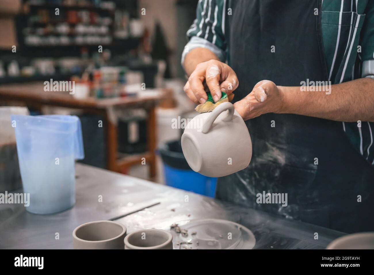 Adult man polishing a clay pot above a table in a workshop Stock Photo ...