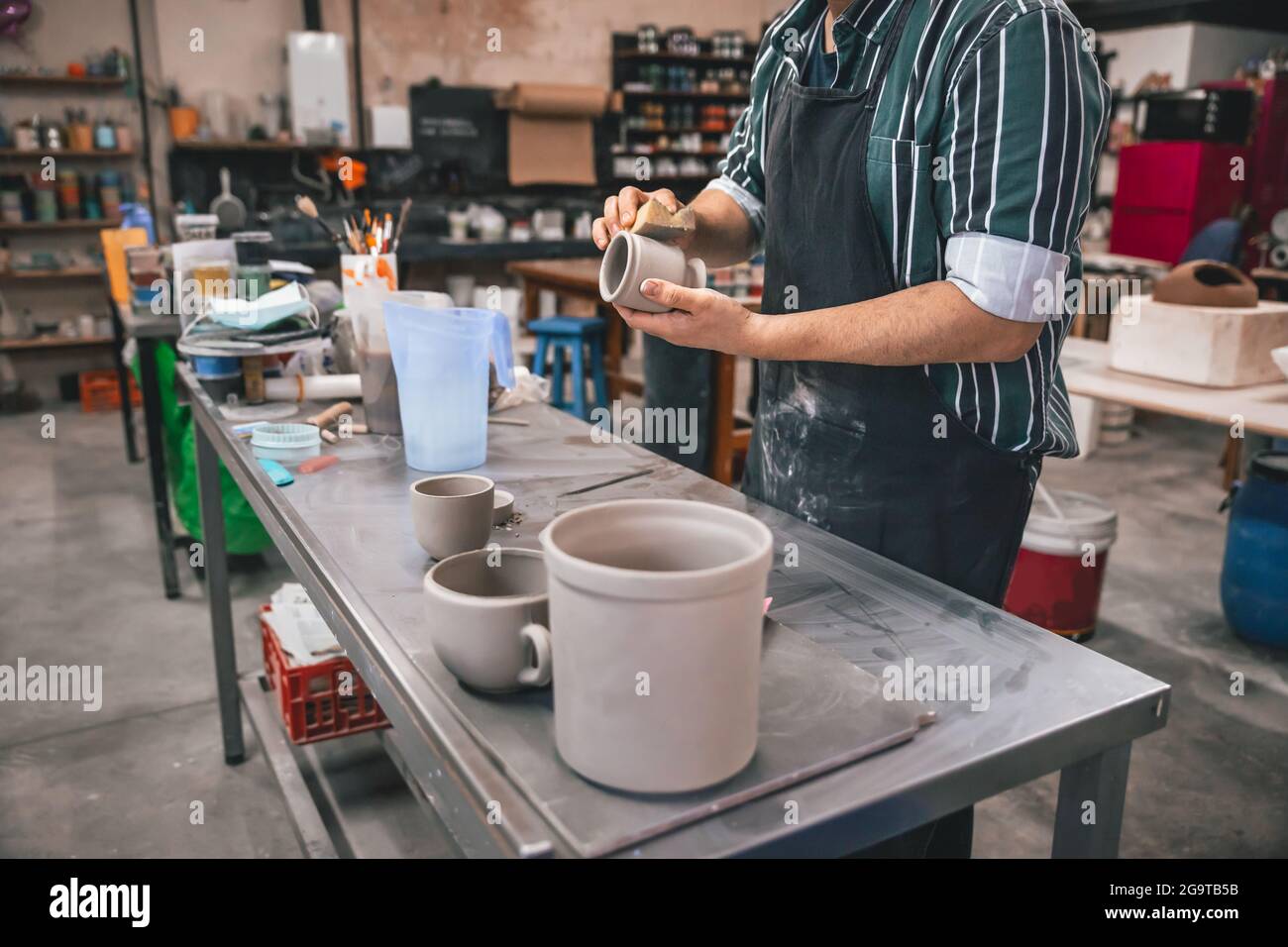 Adult man polishing a clay pot above a table in a workshop Stock Photo ...