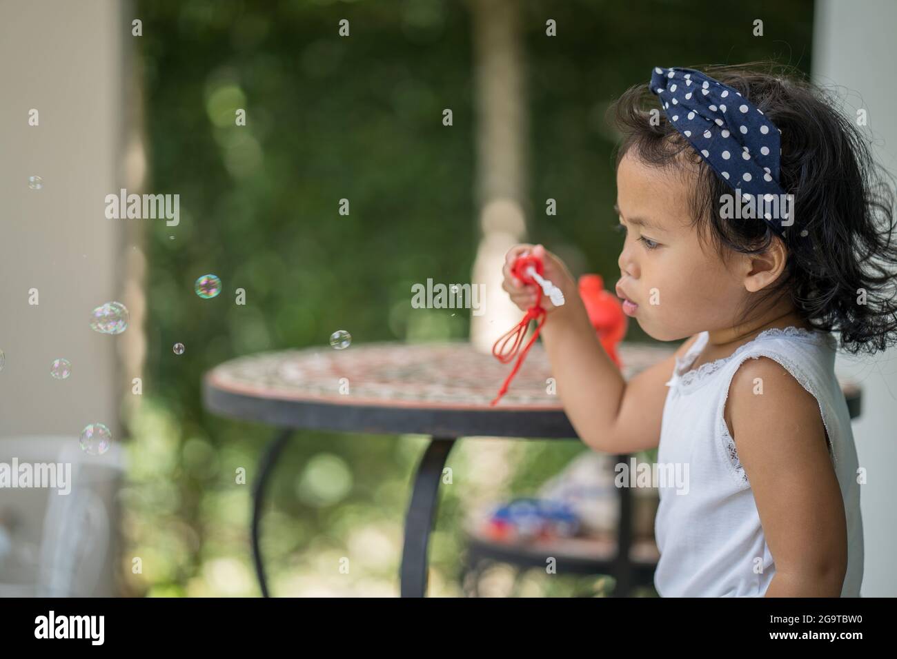 Cute Asian female child blowing bubbles Stock Photo - Alamy