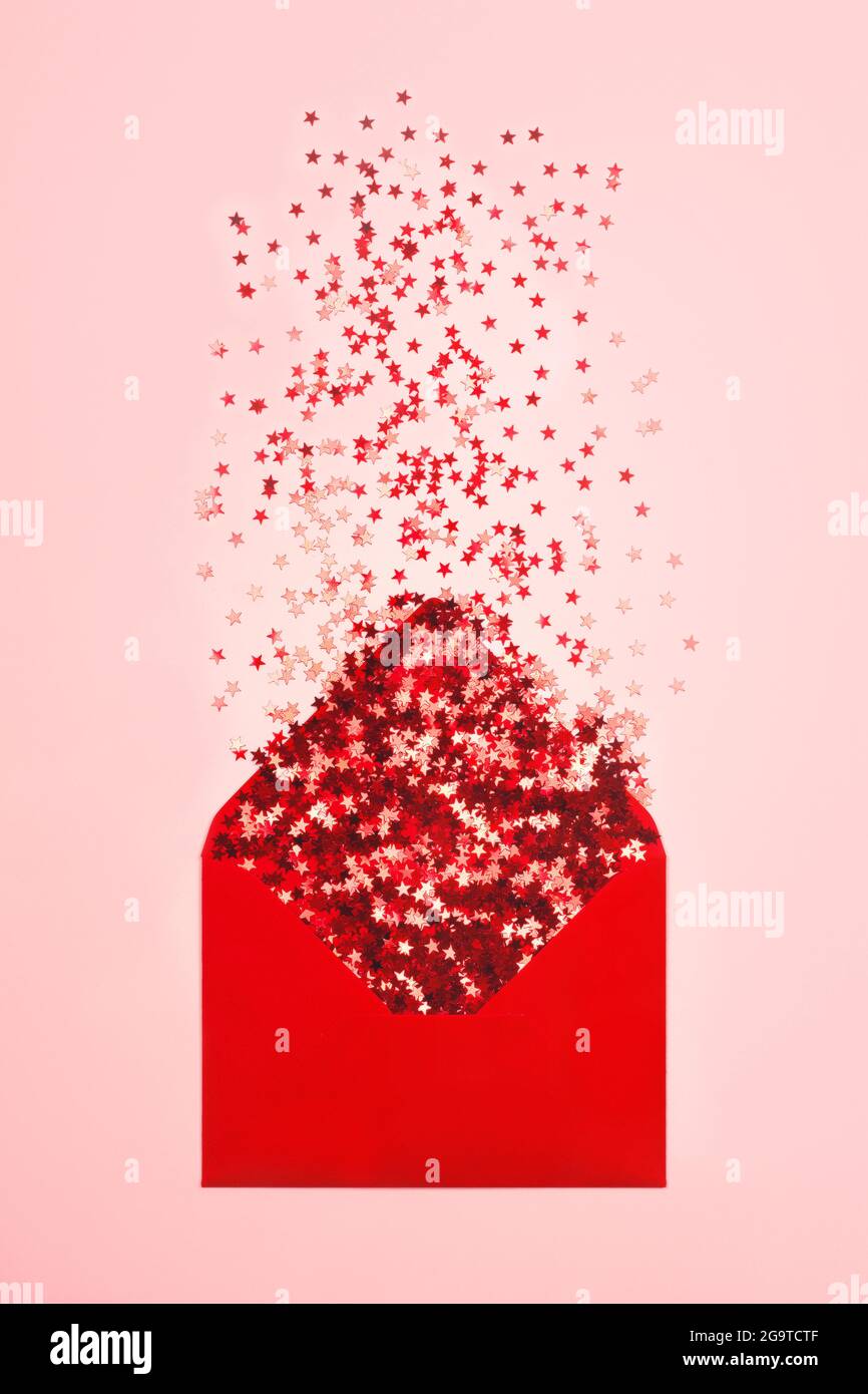Red star shaped confetti pouring out of red envelope on pink background ...