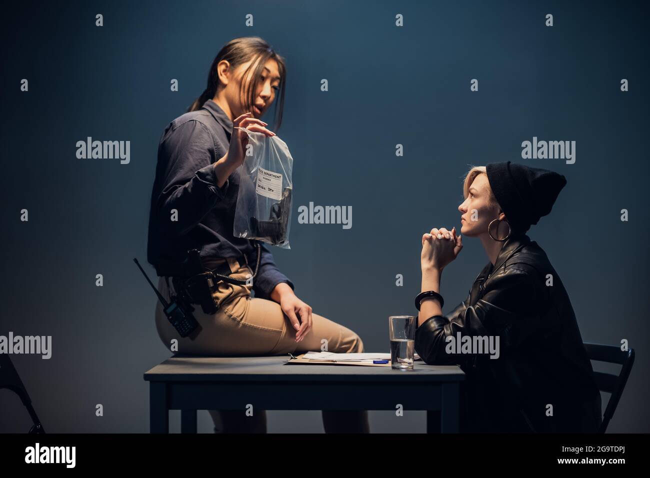 A young asian female investigator sits on a table and shows a package ...