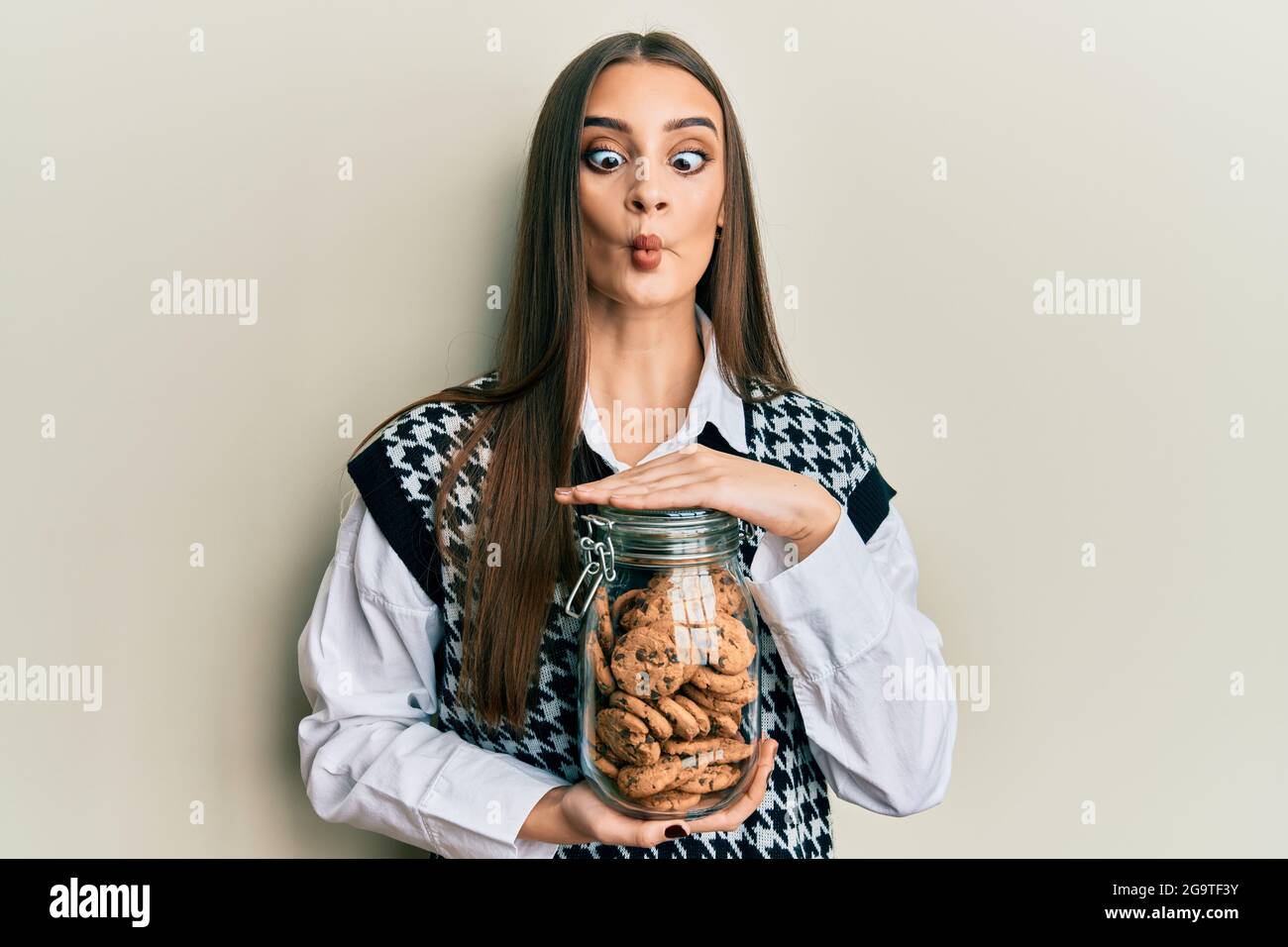 Beautiful brunette young woman holding jar of chocolate chips cookies ...