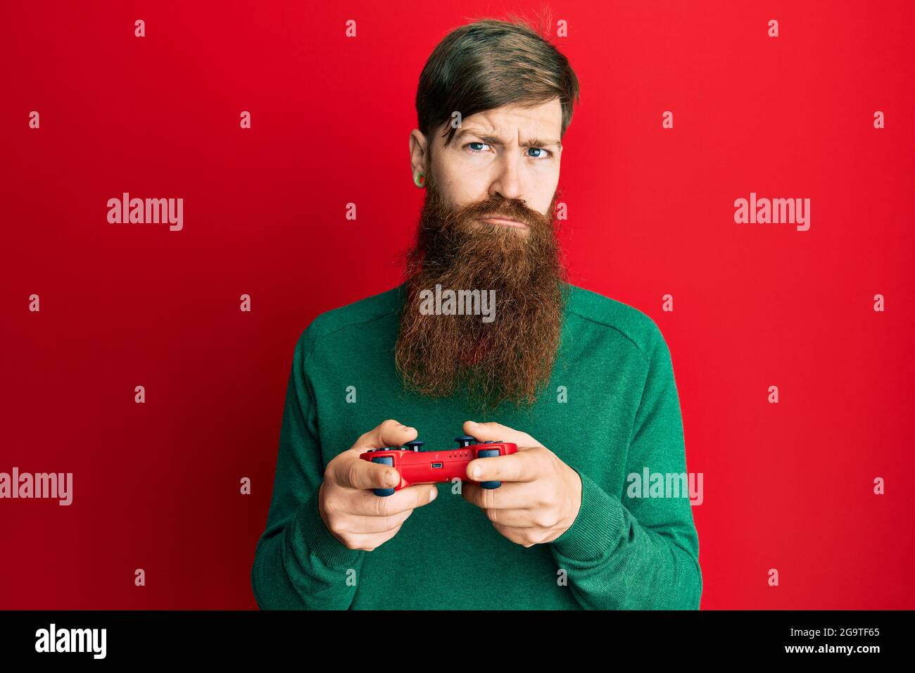 Redhead man with long beard playing video game holding controller ...