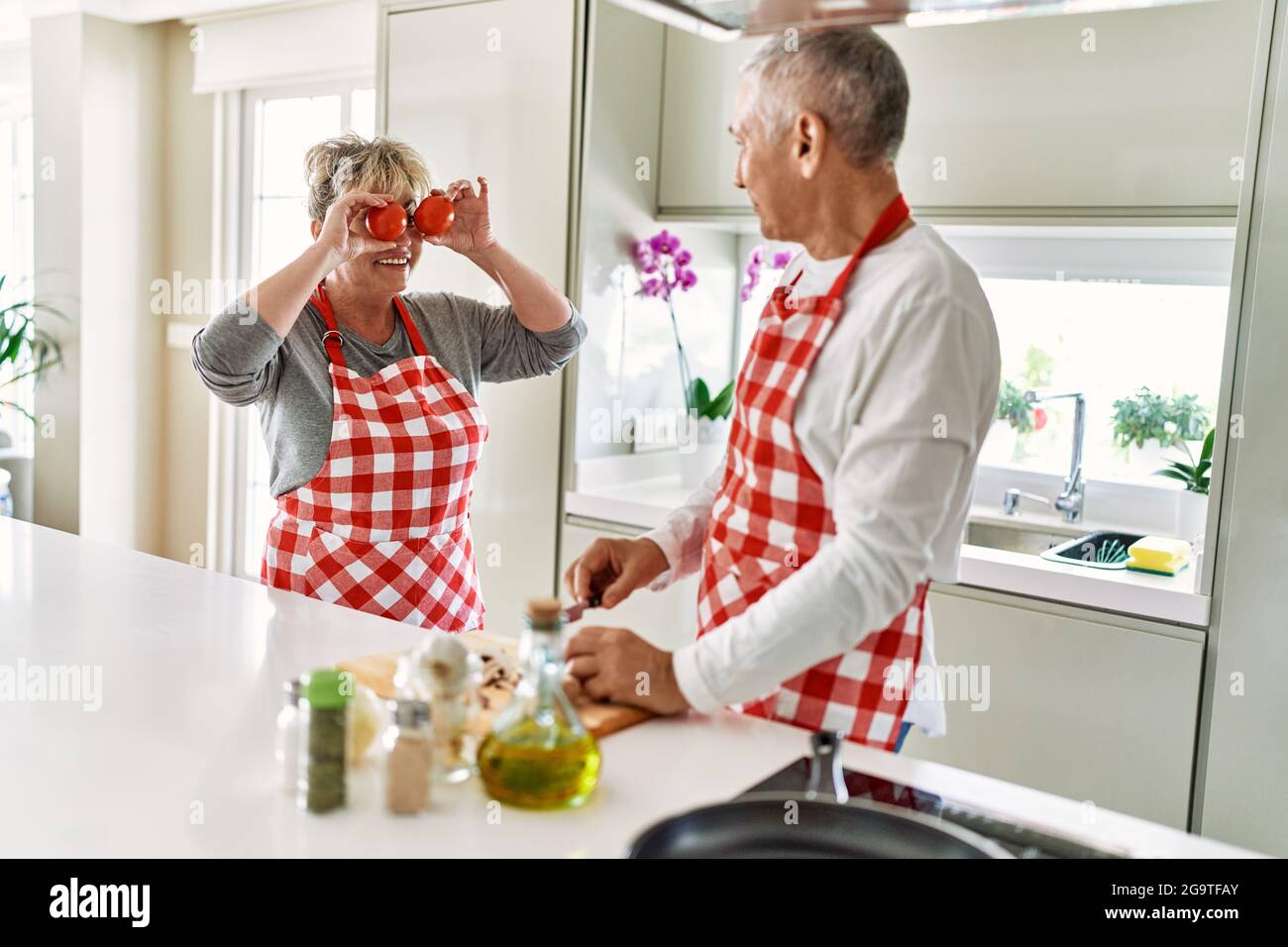 Senior caucasian couple smiling happy cooking at the kitchen. Woman ...