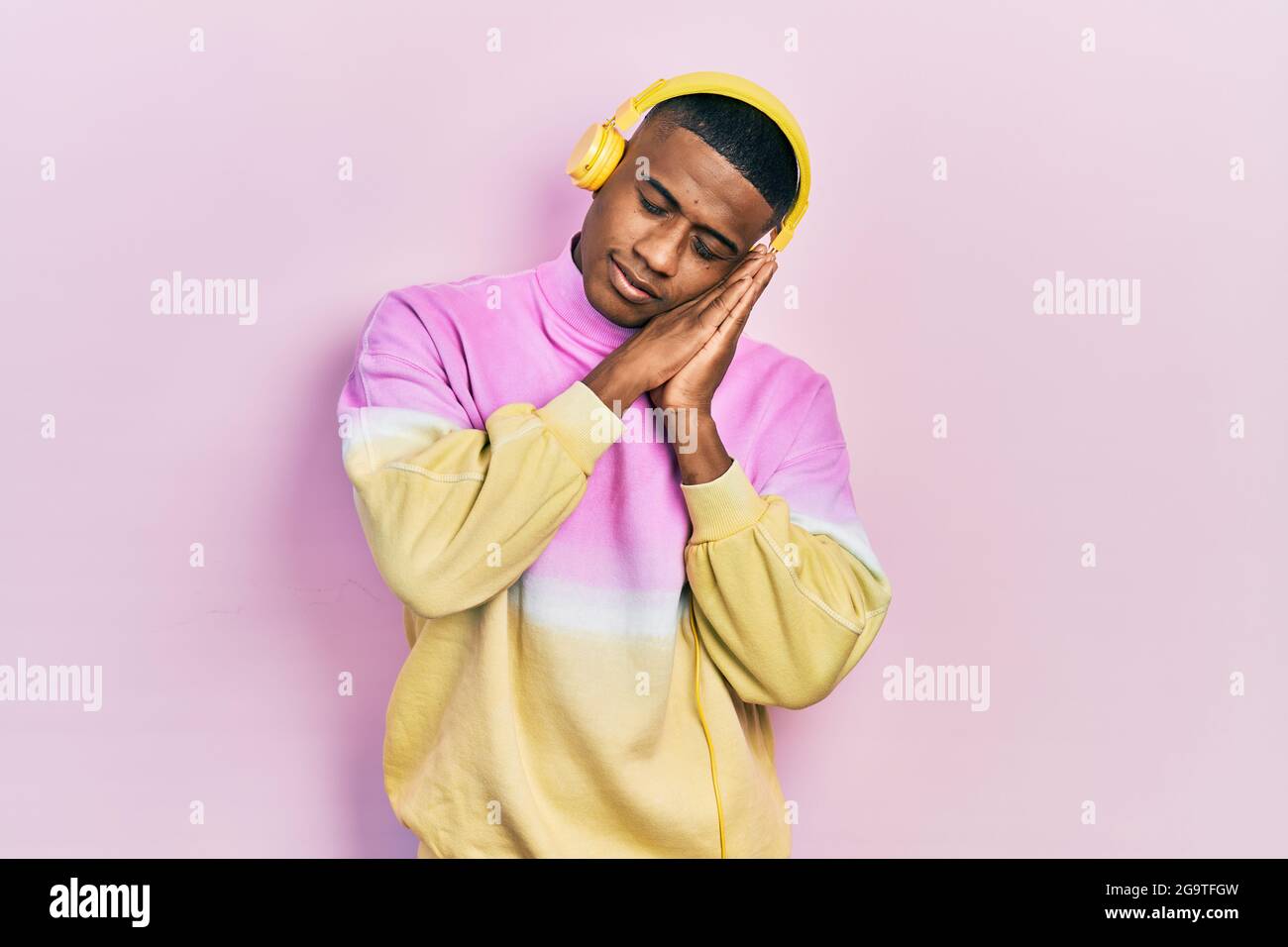 Young black man listening to music wearing headphones sleeping tired ...