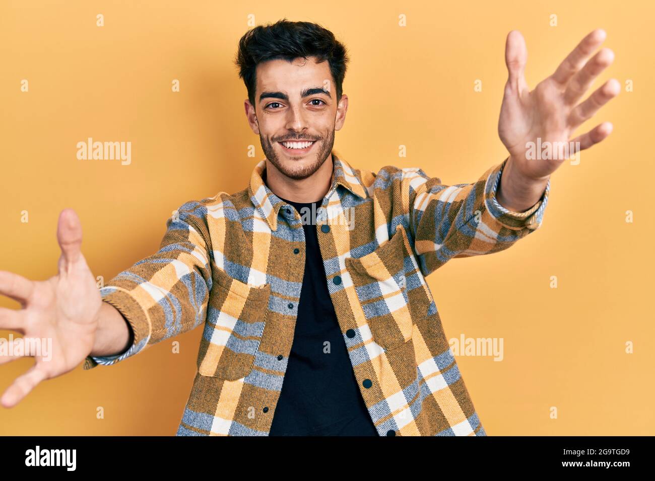 Young hispanic man wearing casual clothes looking at the camera smiling ...