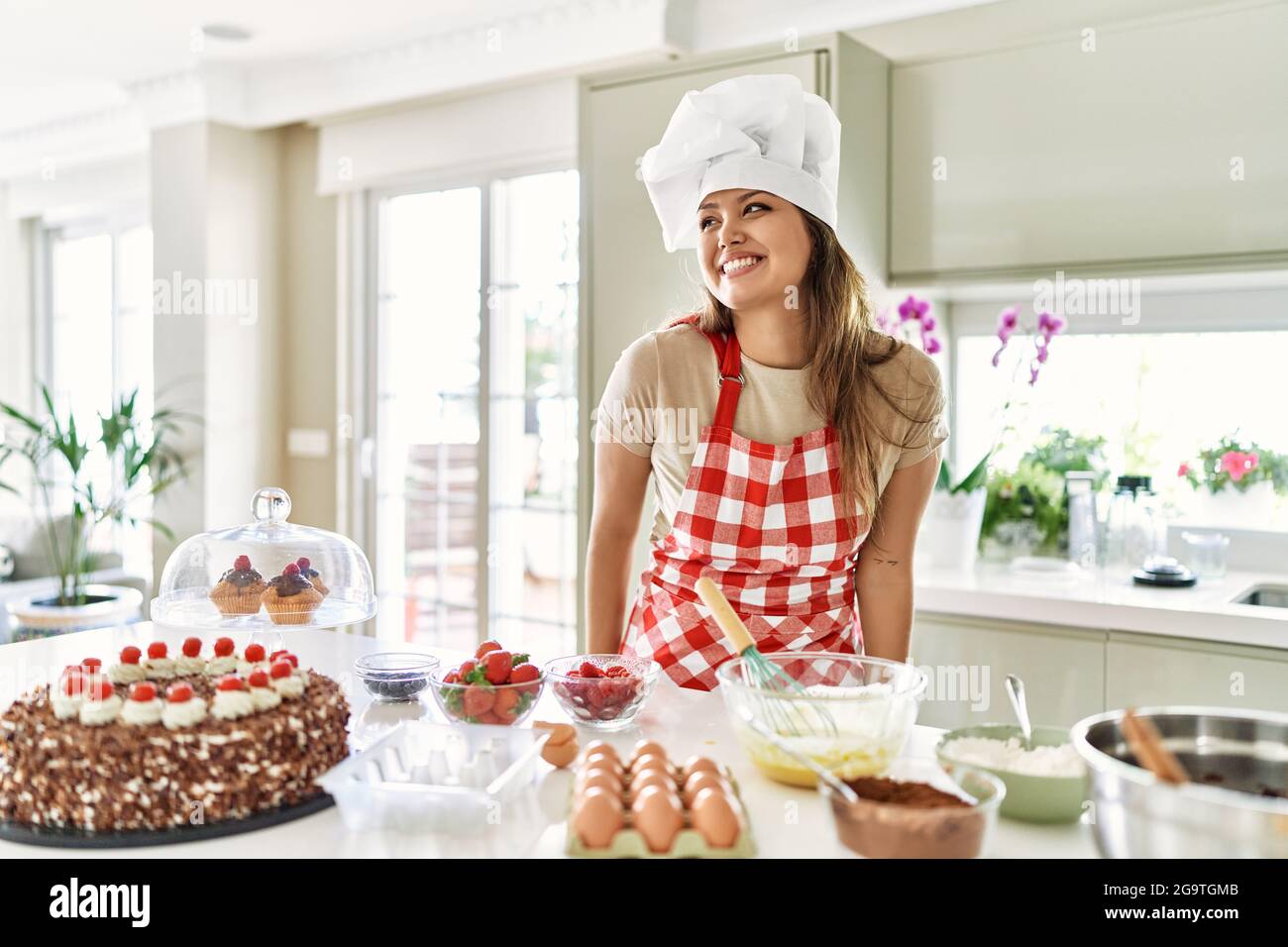 Beautiful young brunette pastry chef woman cooking pastries at the ...