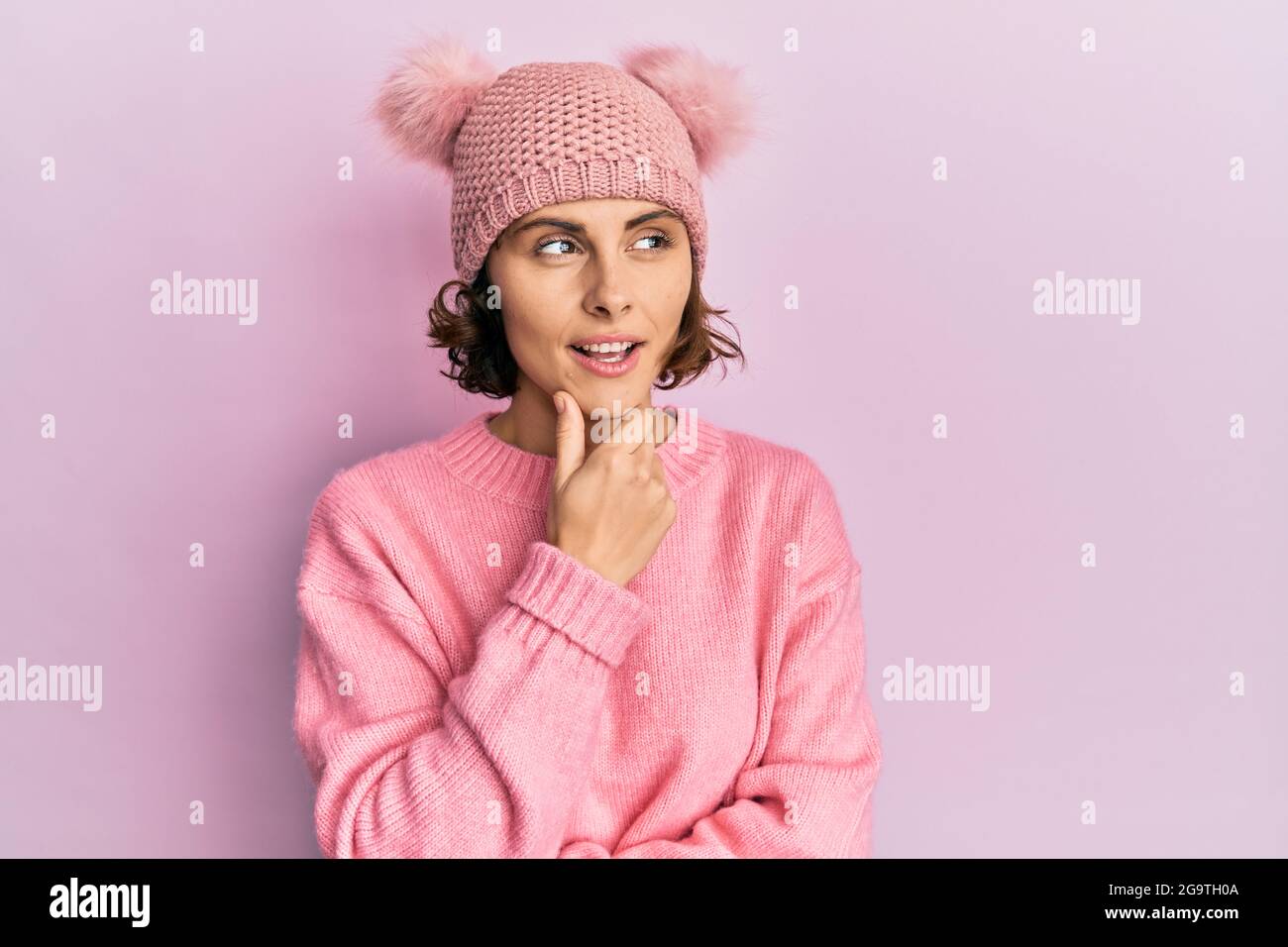 Young brunette woman wearing cute wool cap with hand on chin thinking ...