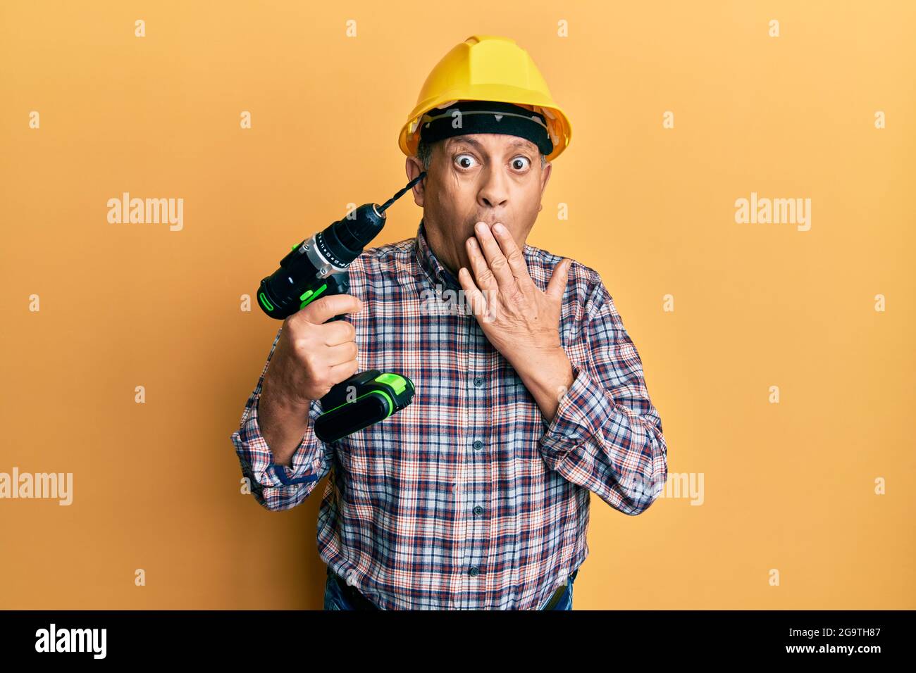 Handsome senior man with grey hair holding electric screwdriver wearing ...